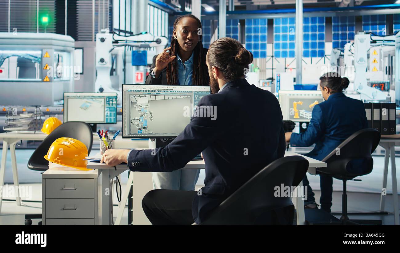 Photovoltaics factory production manager looking over schematics, instructing worker on ...
