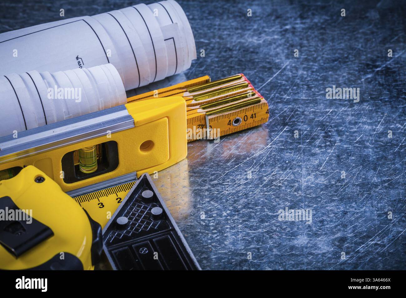 Construction level blueprints and measurement tools on metallic ...