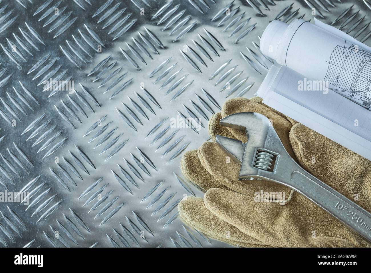 Blueprints adjustable wrench protective gloves on fluted metal sheet ...