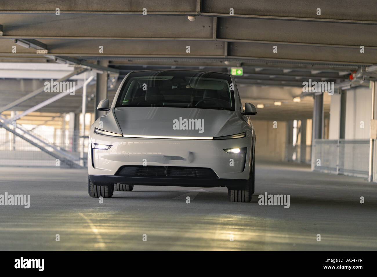White car with modern lines in a car park illuminated by neon lights ...