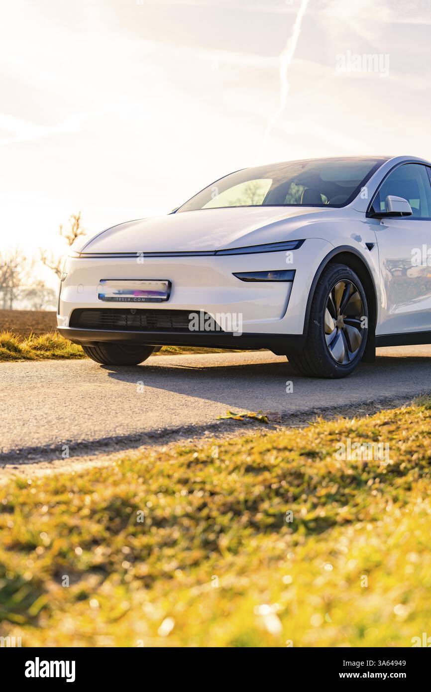 White car illuminated by the low sun on a country road, Tesla, New ...