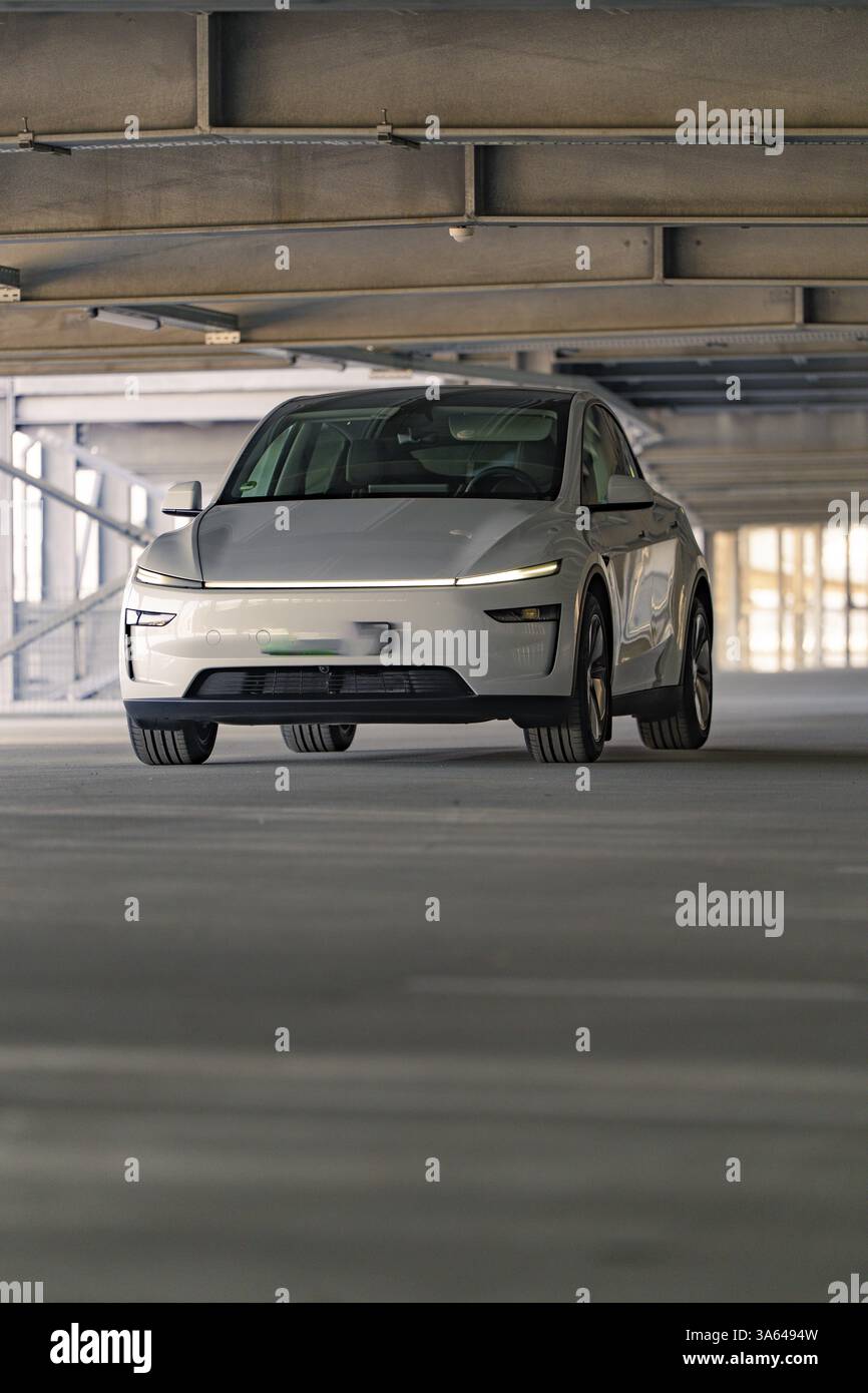 White car parked in a grey, sparsely lit car park, Tesla, New Model Y ...