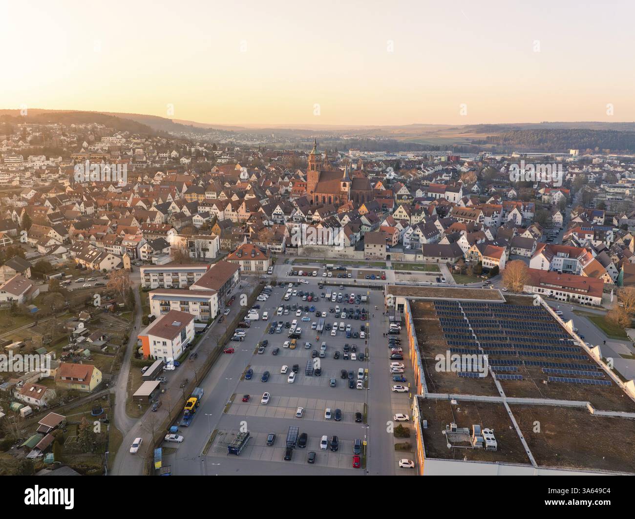 Aerial view of a town with a church tower, many houses and a large car ...
