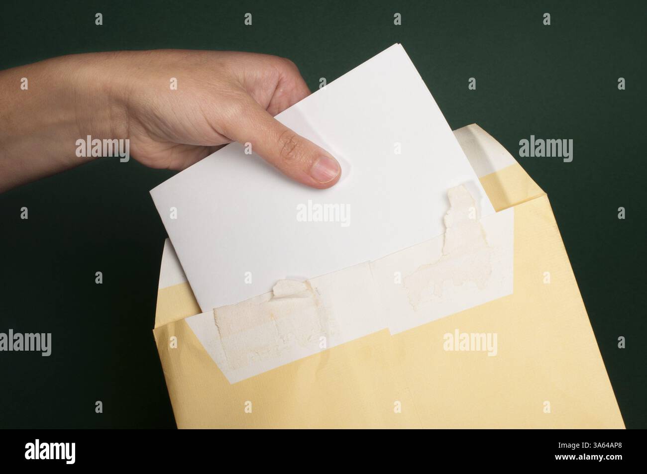 Hand that open a letter from brown envelope. Dark green background ...