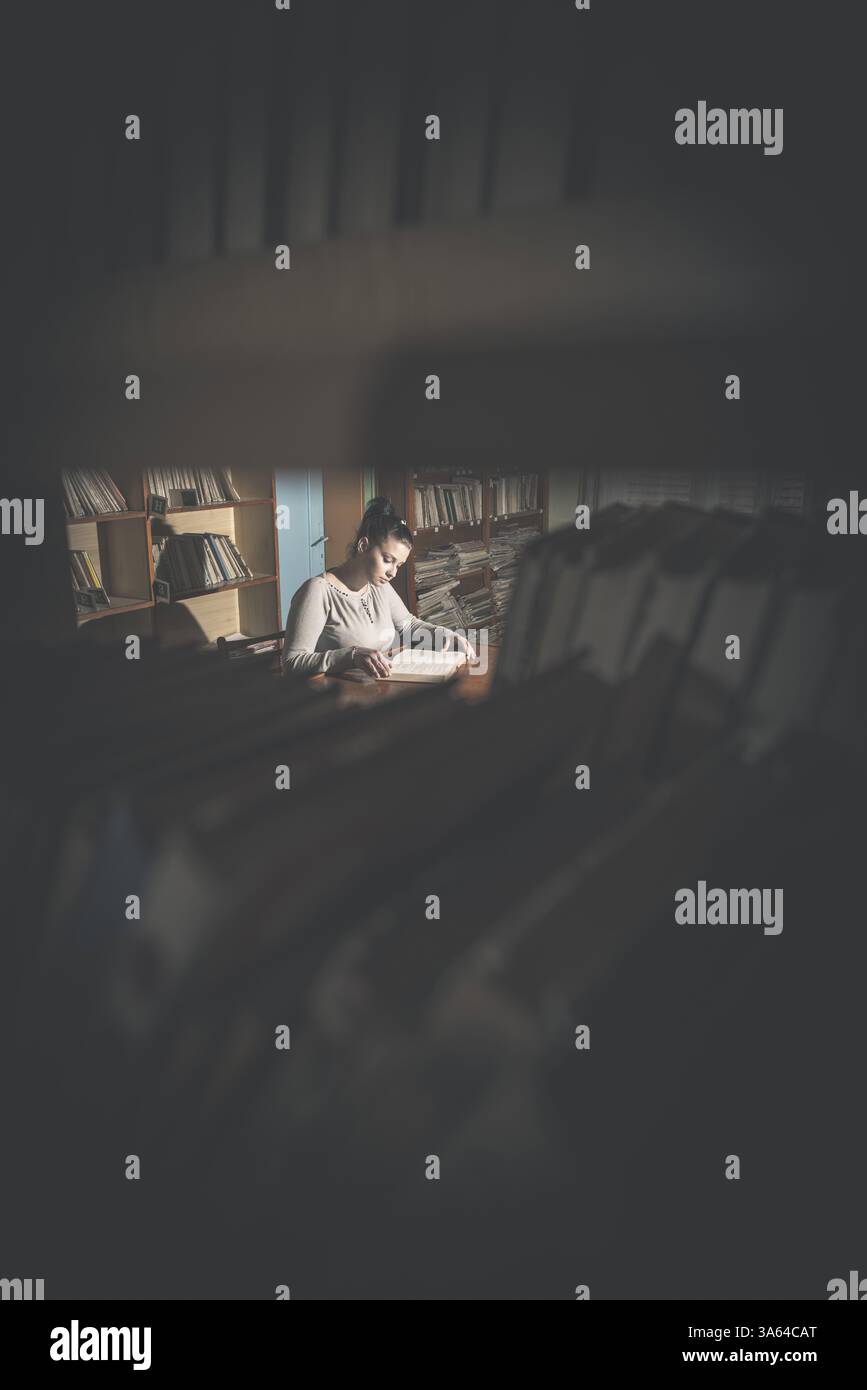 Student girl in a library. Looking at book Stock Photo - Alamy
