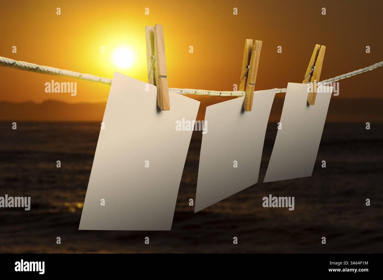 Note papers hooked on a rope. Sunset background Stock Photo - Alamy