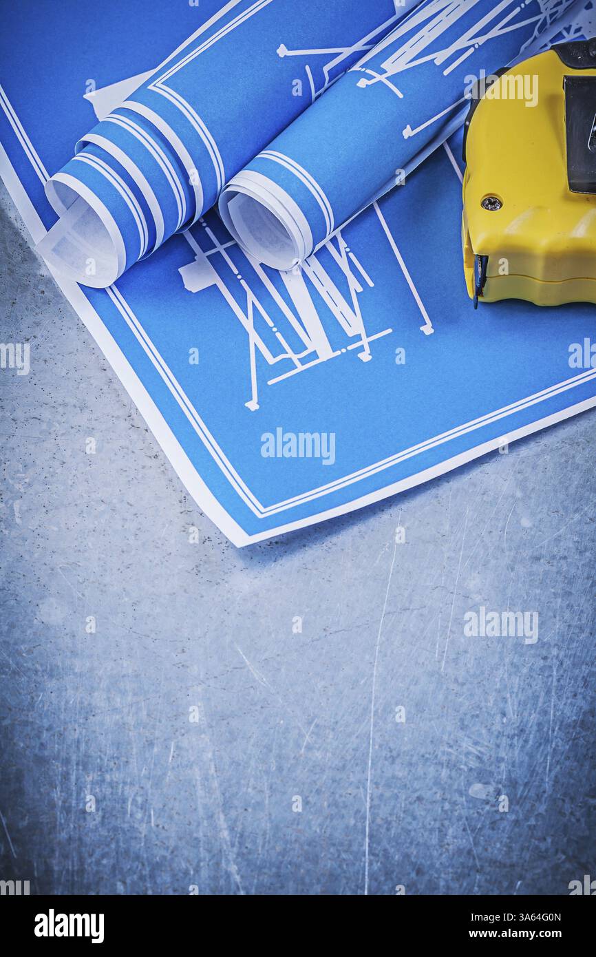 Composition of blue blueprints measuring tape on scratched metallic ...