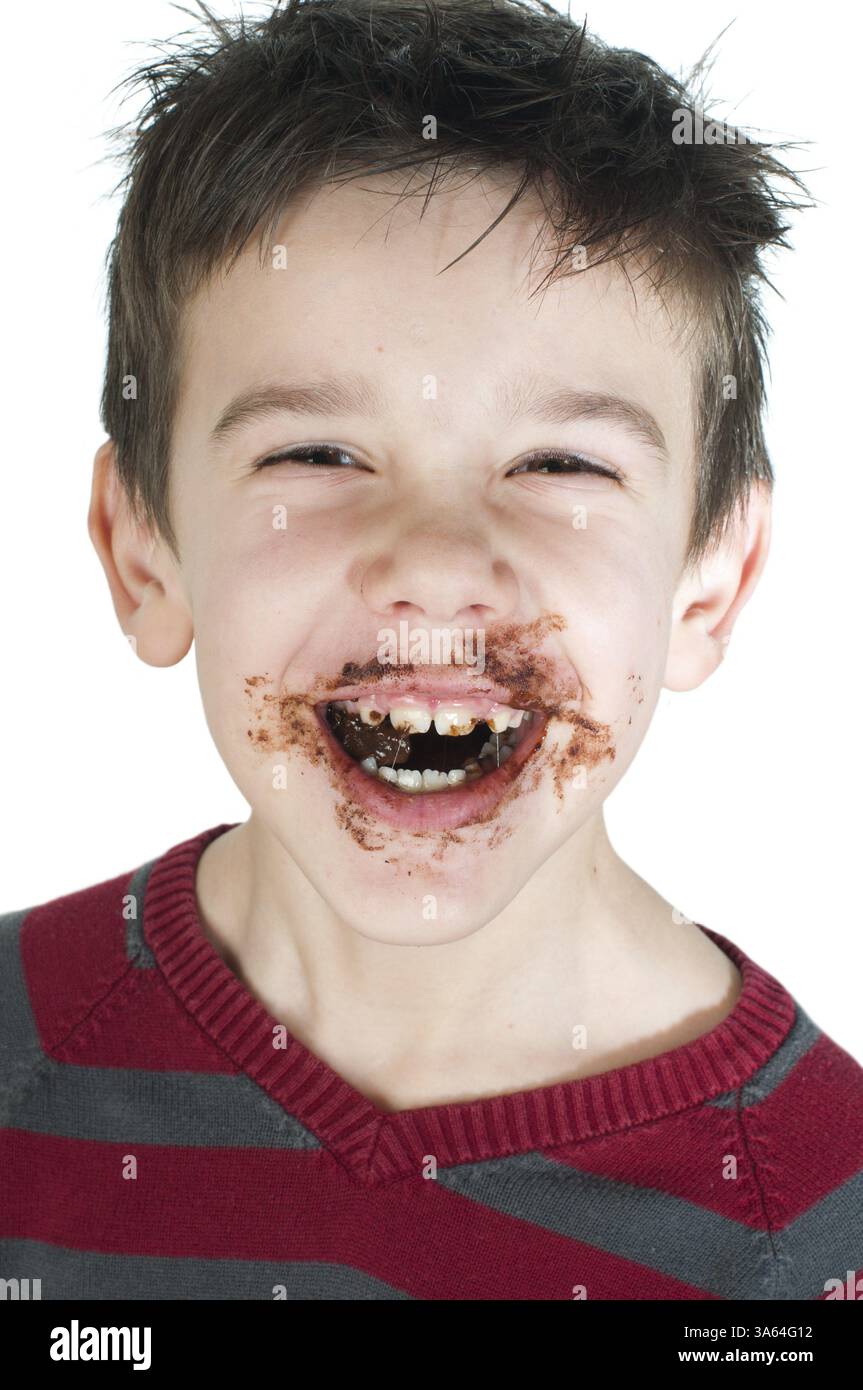Smiling kid eating chocolate. Smeared stained with chocolate lips ...