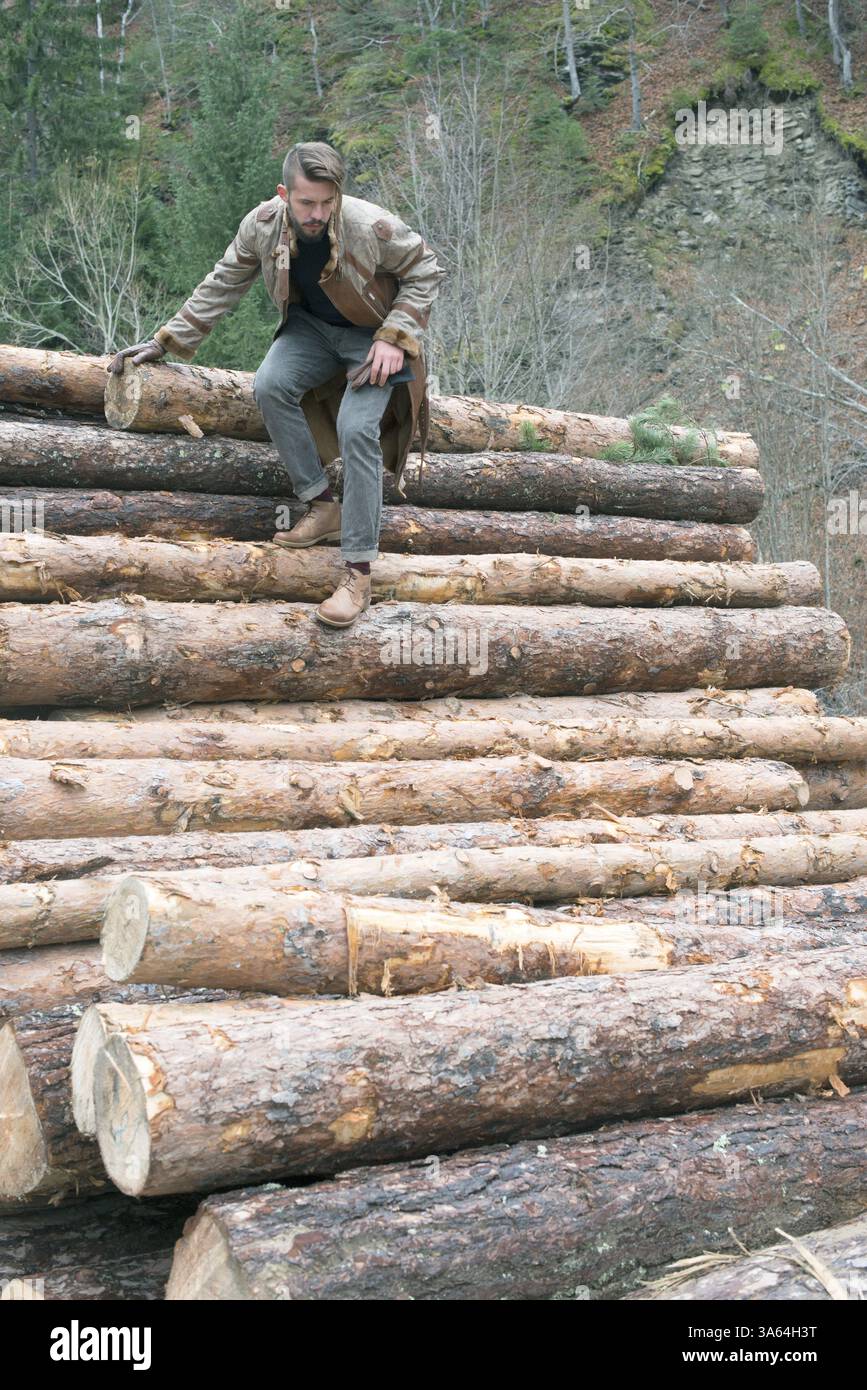 Young men on logs in the forest. Leather and jeans. Outdoor fashion ...