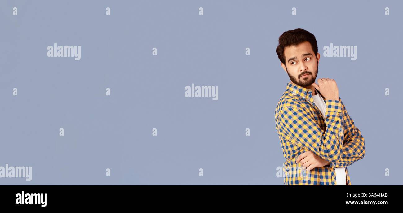 Thoughtful Indian guy looking over his shoulder at empty space, lilac ...