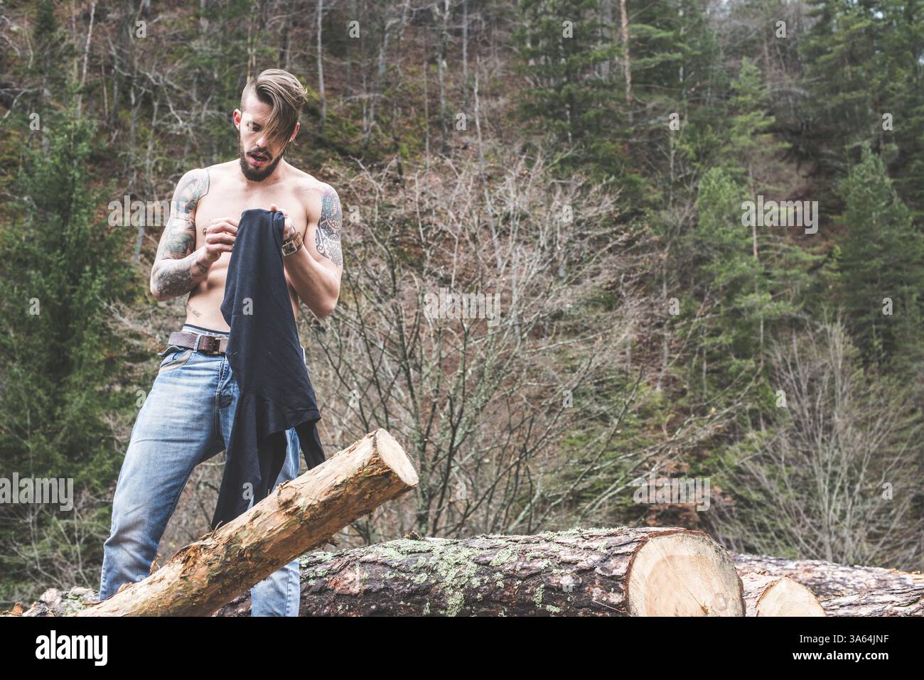 Young men on logs in the forest. Men dress Stock Photo - Alamy
