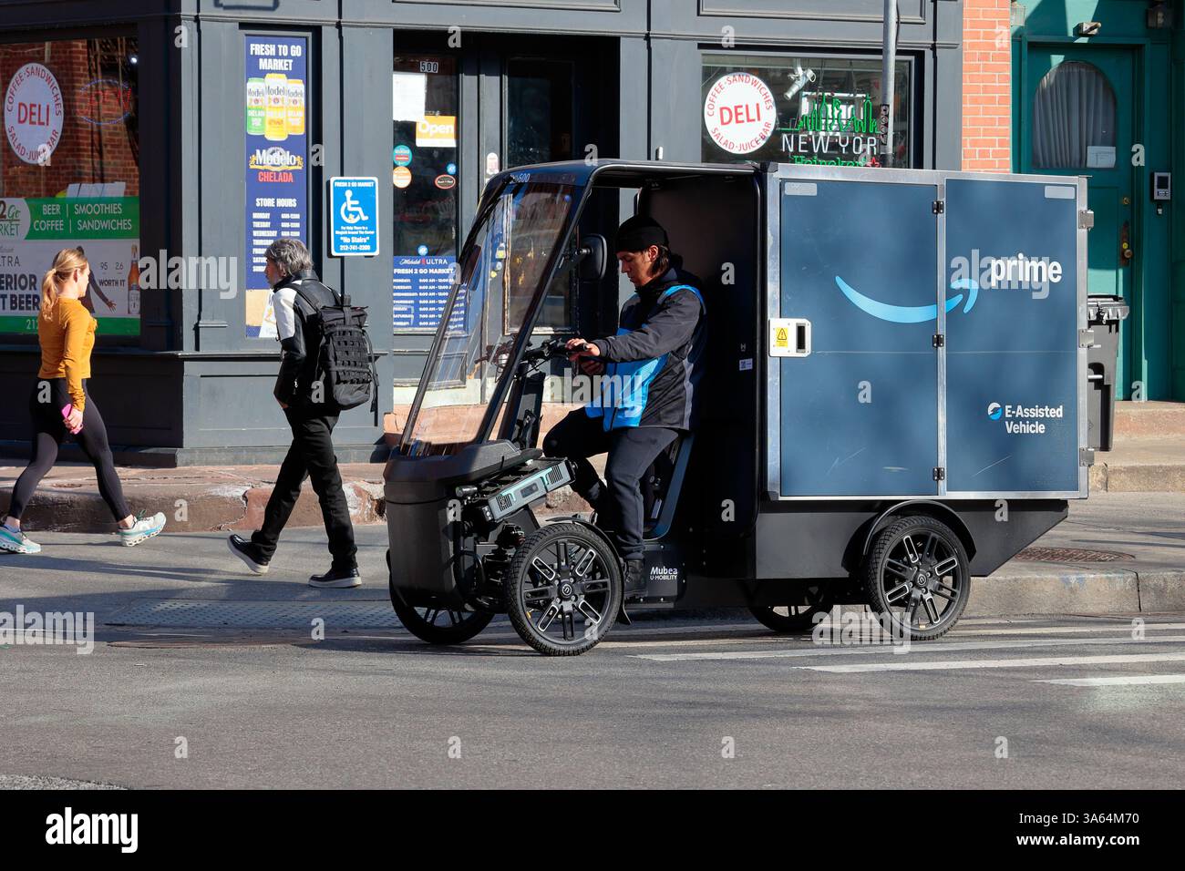 A delivery person in an Amazon branded Mubea U-Mobility 4 wheeled electric cargo bike on a NYC ...