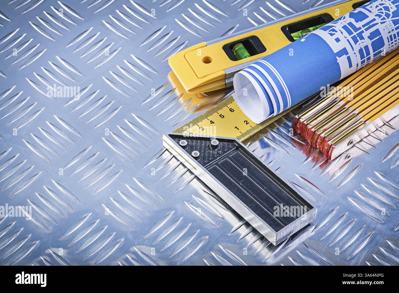 Construction level wooden meter blue rolled blueprints try square on grooved metal plate Stock ...