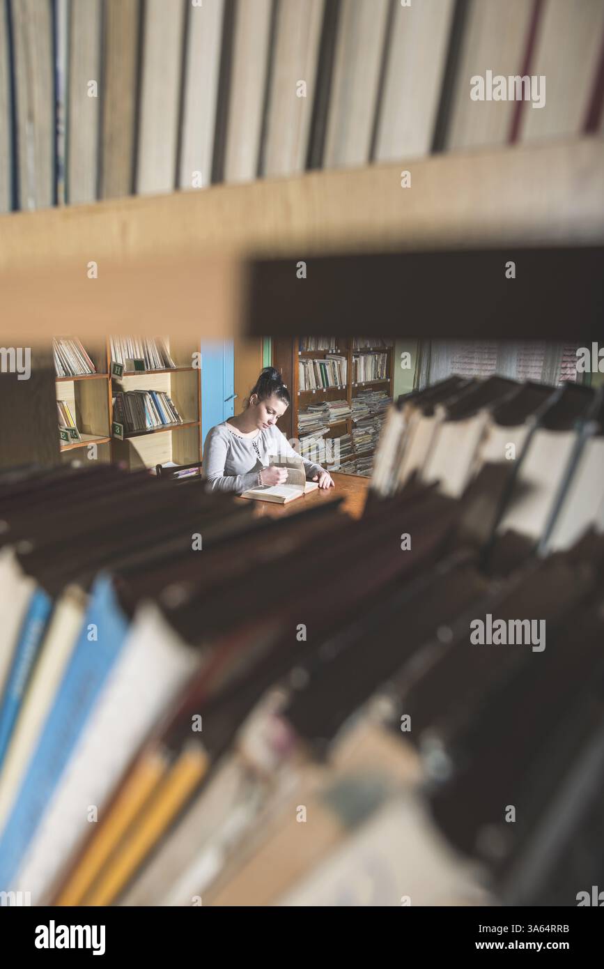 Student girl in a library. Looking at book Stock Photo - Alamy