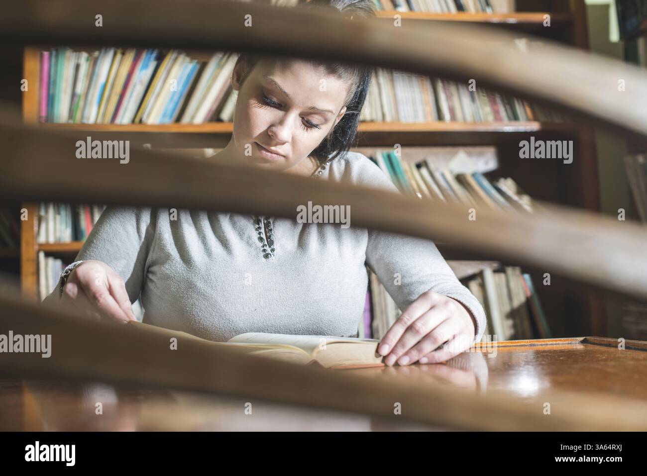 Student girl in a library. Looking at book Stock Photo - Alamy