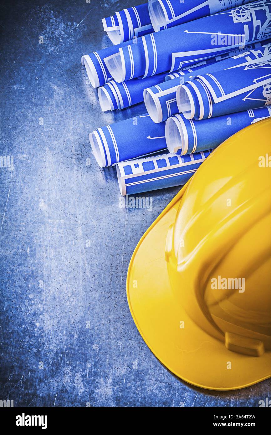 Blue engineering drawings yellow building helmet on scratched metallic ...