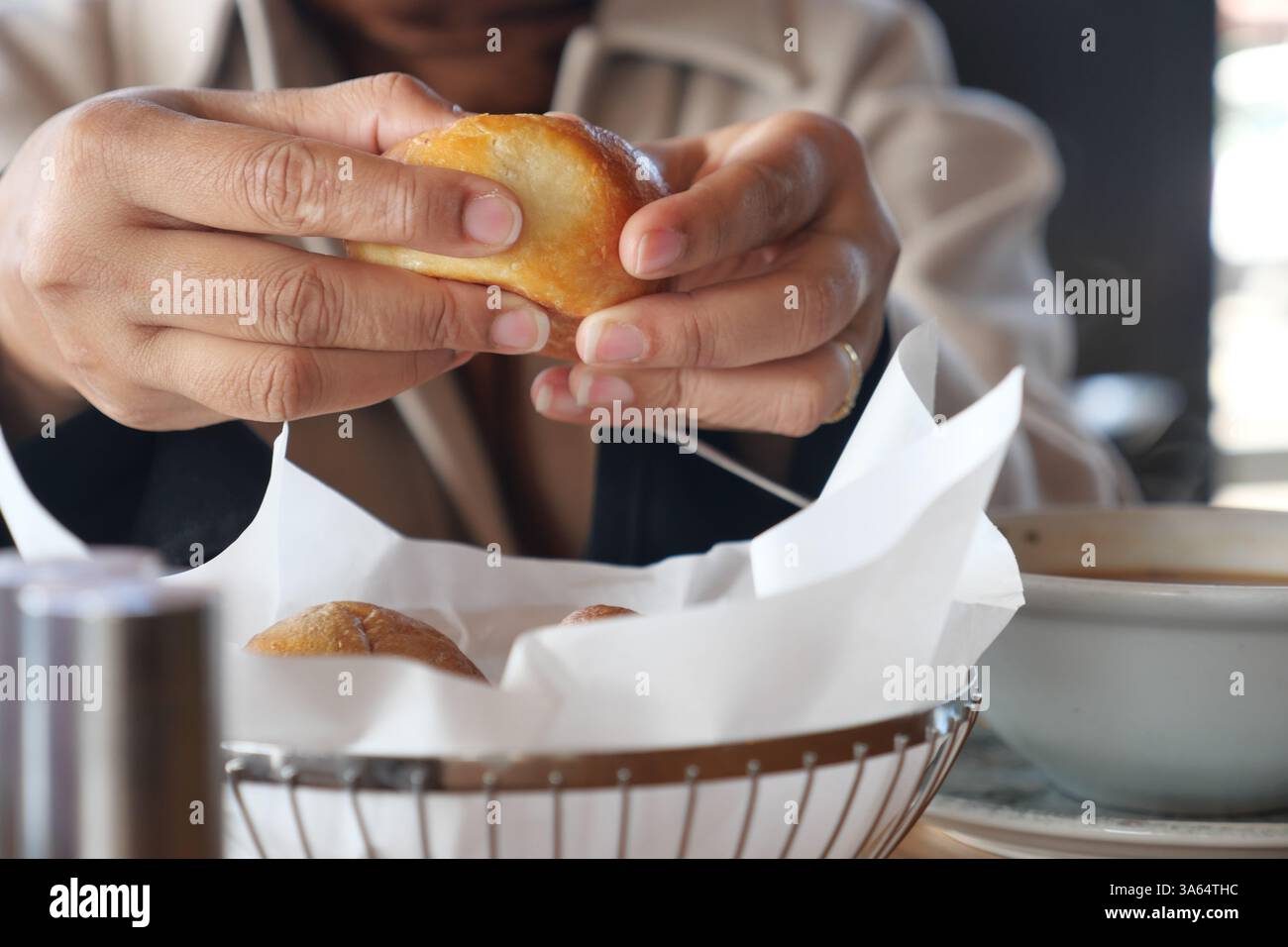 Hands breaking bread while enjoying a warm meal in a cozy cafe Stock ...