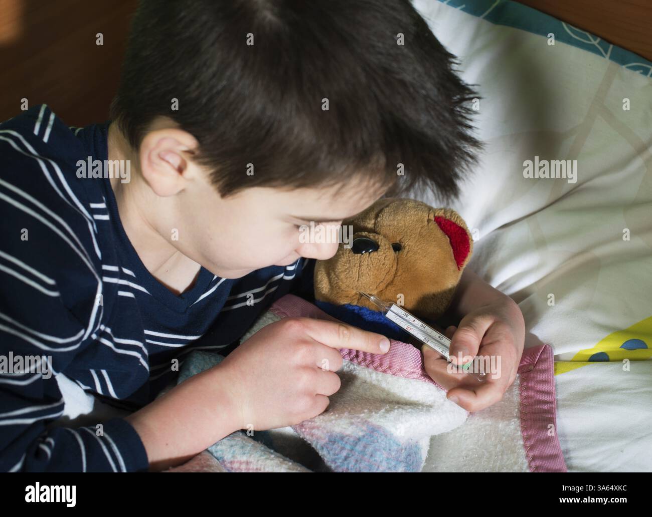 Sick child in bed with teddy bear. Measuring the temperature with a ...