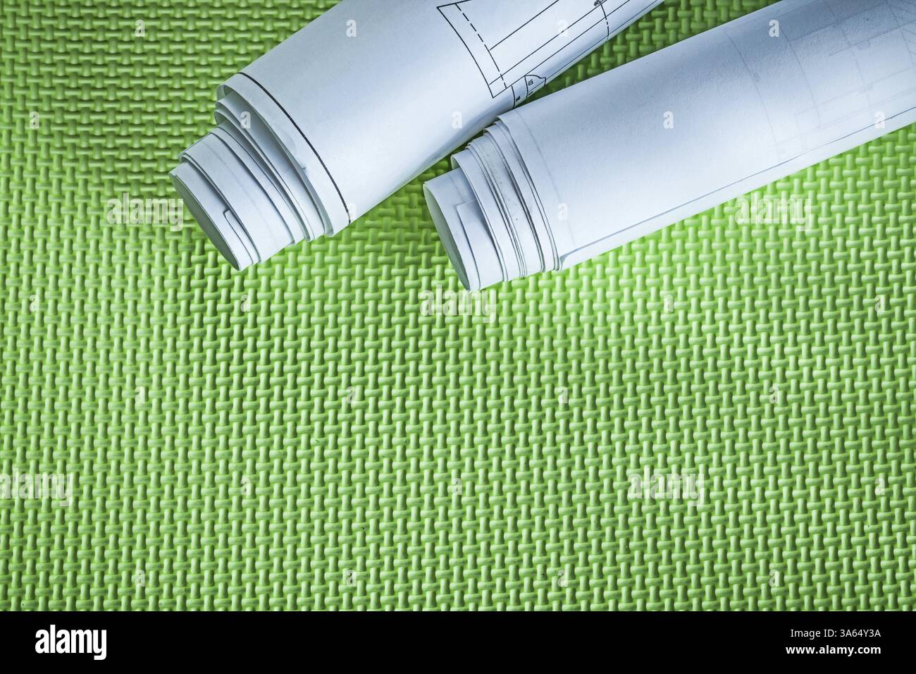 Rolled up construction drawings on green surface building concept Stock ...