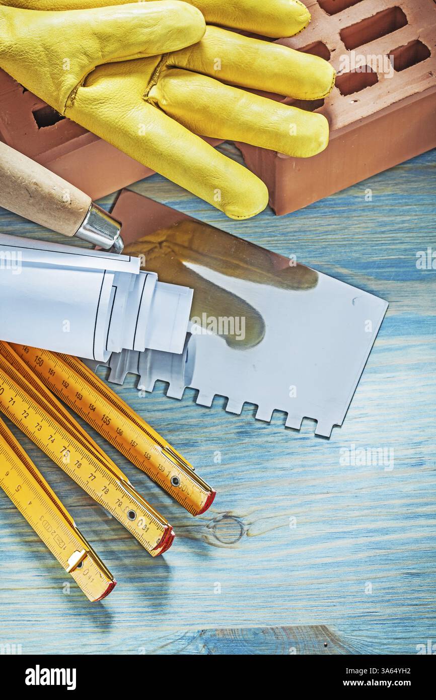 Red bricks working gloves blueprints wooden meter palette knife on wood ...
