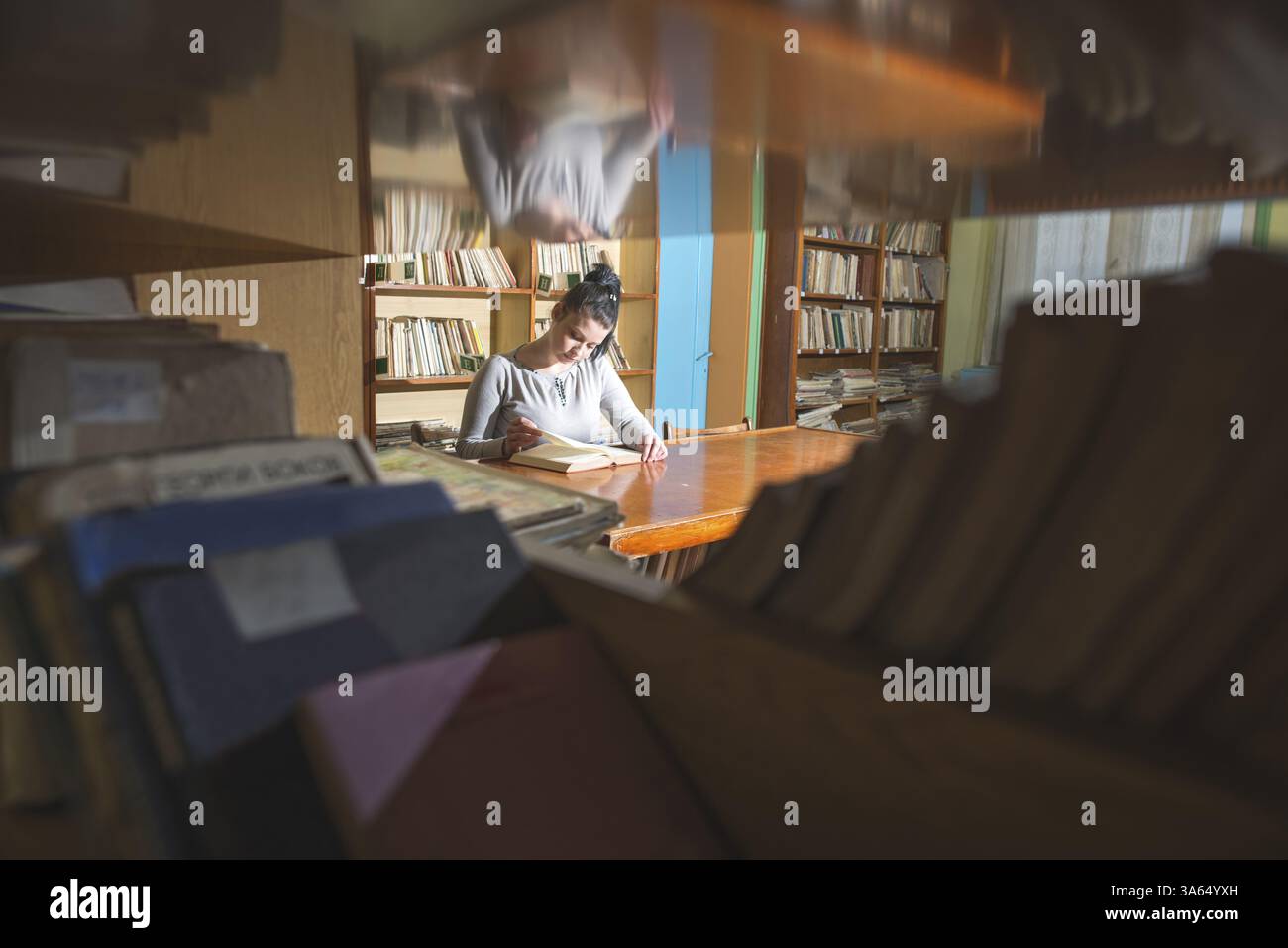 Student girl in a library. Looking at book Stock Photo - Alamy