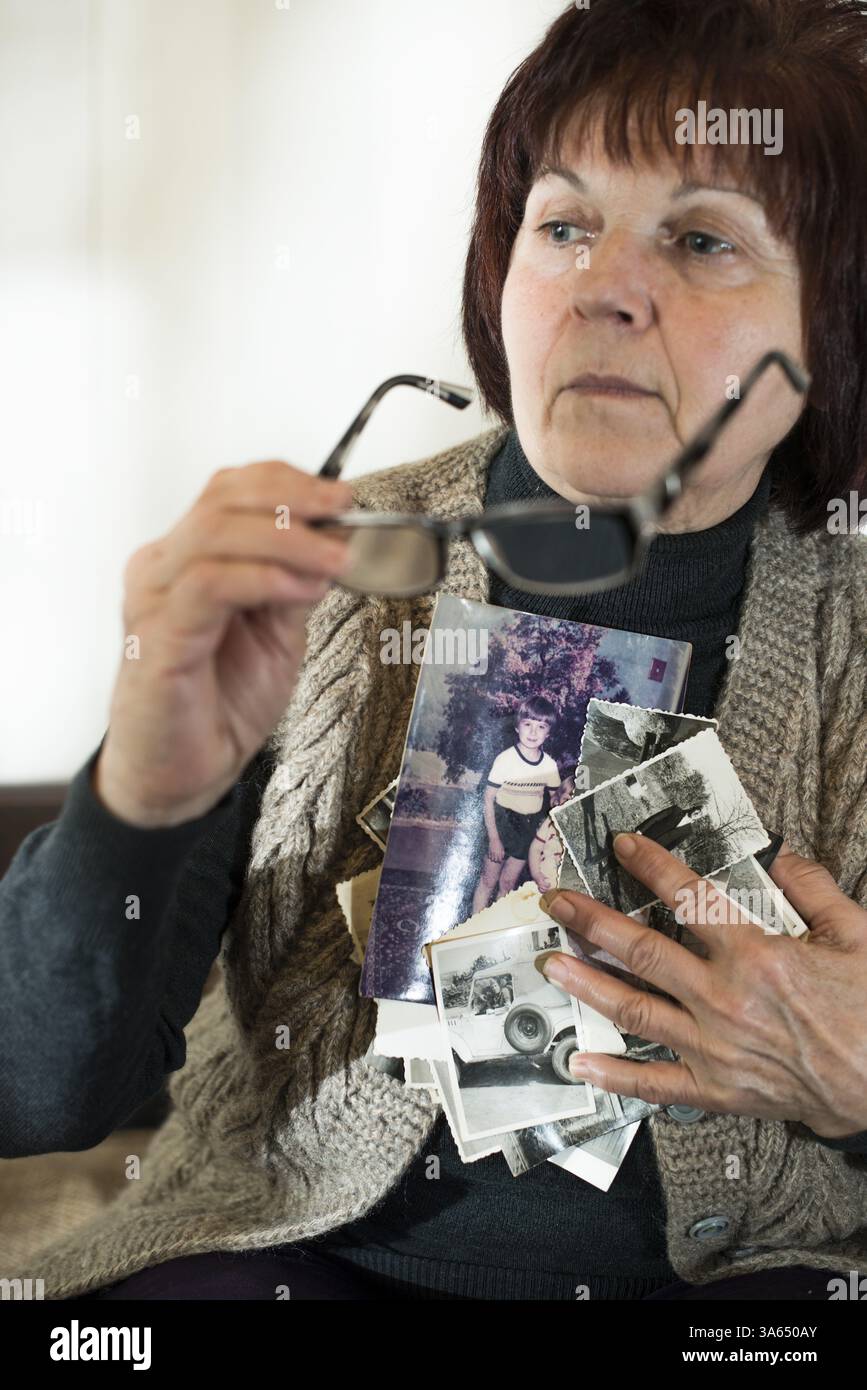 Senior woman watching old photos. Sadness Stock Photo - Alamy