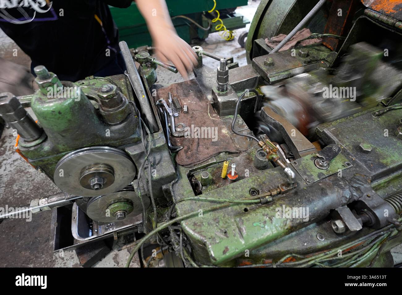 A worker feeds steel wire to machines making screws at Komar Screw Corp ...