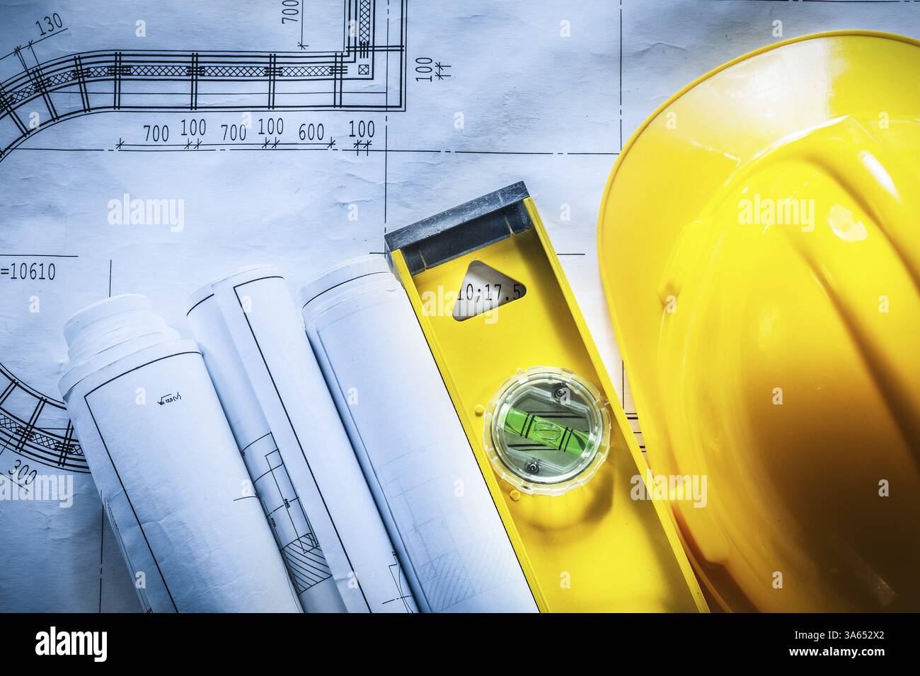 Hard hat construction level plans on blueprint Stock Photo - Alamy