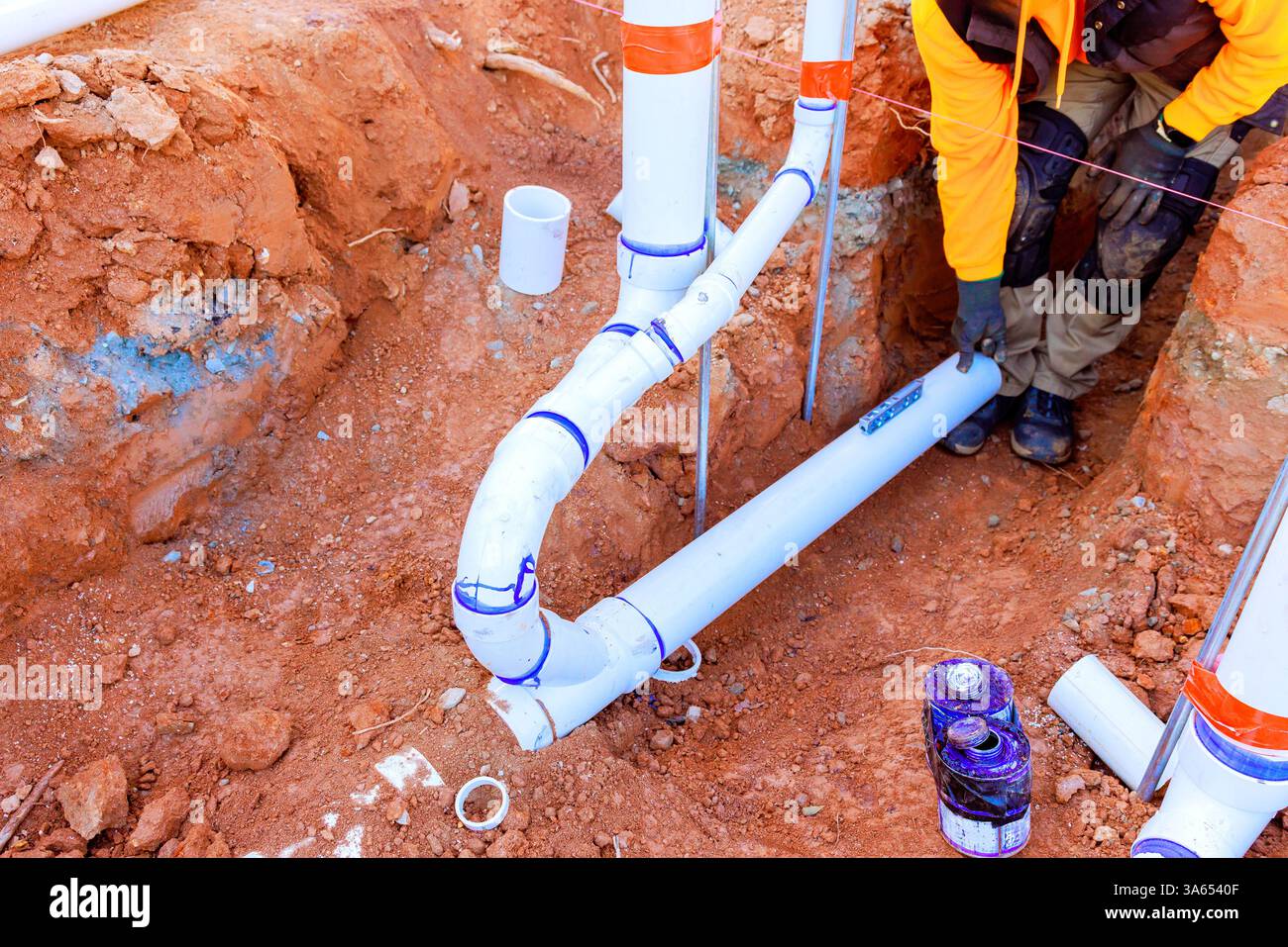 Worker is connecting PVC pipes in trench, ensuring proper alignment at ...