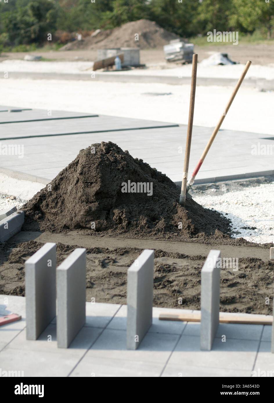 Tiling of pavement and sand pile. Two shovels Stock Photo - Alamy