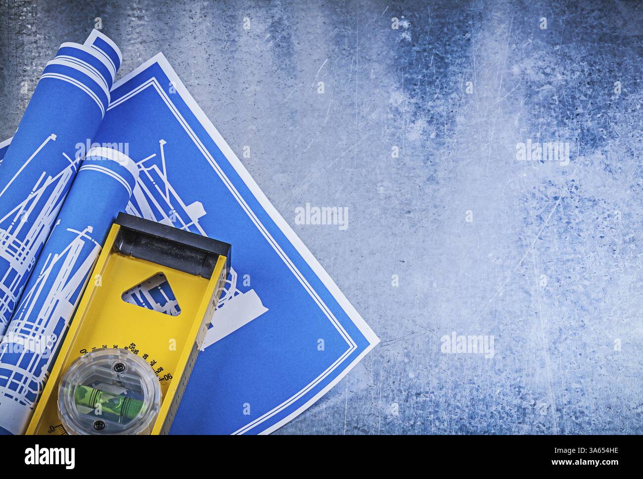 Blue rolled blueprints yellow construction level on metallic background ...