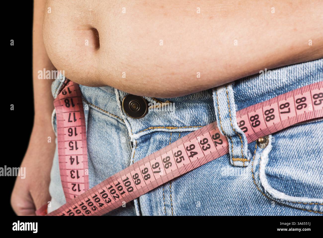 Woman showing fat belly. Pink tape measure Stock Photo - Alamy