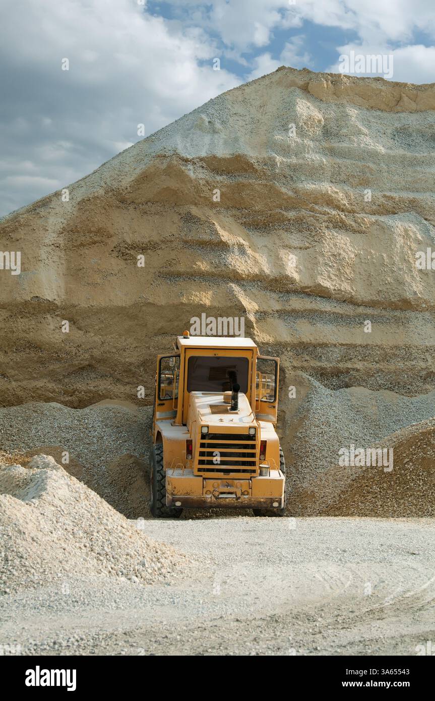 Bulldozer in quarry. Huge pile of limestone and sand Stock Photo - Alamy