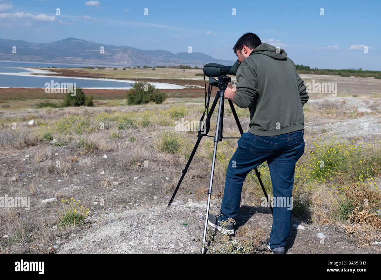 Young man birdwatching with a telescope by a lake Stock Photo - Alamy