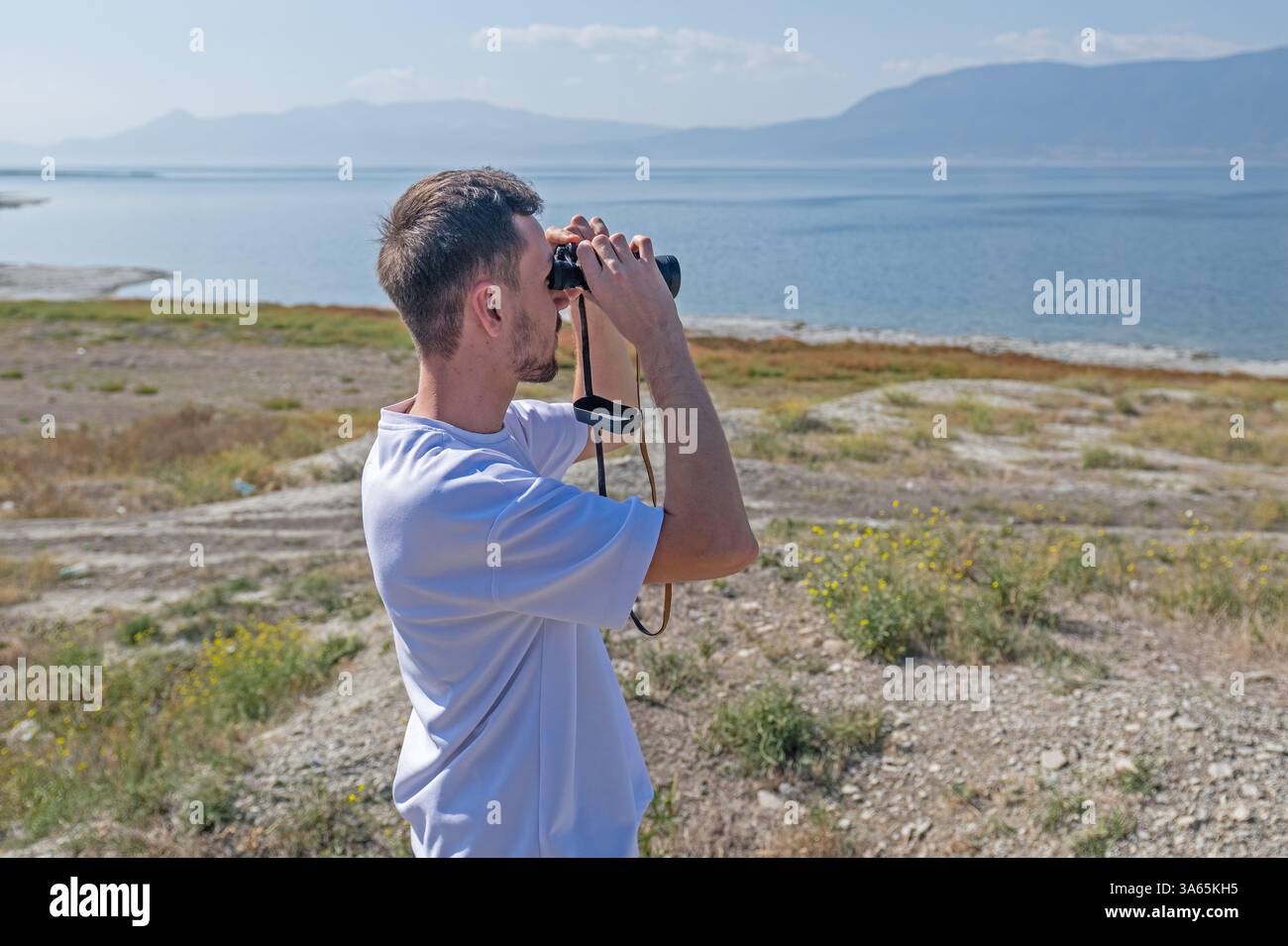 Young man birdwatching with a telescope by a lake Stock Photo - Alamy