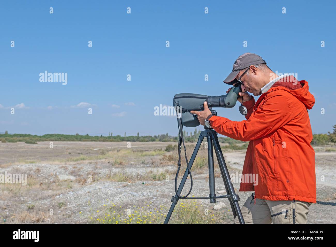 A man birdwatching with a telescope by a lake Stock Photo - Alamy