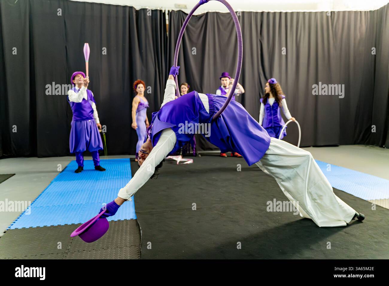 Circus artist hangs upside down from an aerial hoop, performing a ...