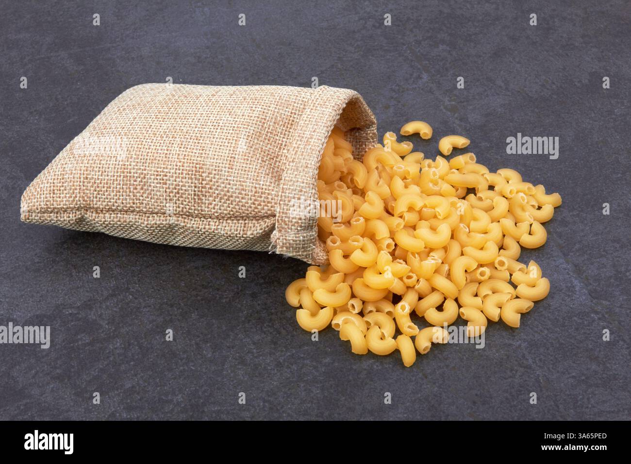 Elbow macaroni in bag on black background Stock Photo - Alamy