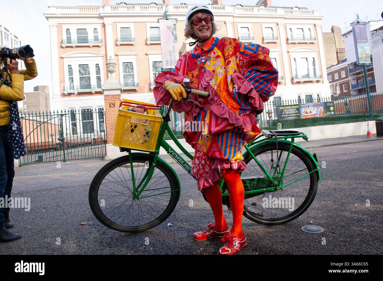 London, UK. 25th Mar, 2025. Artist and performer Grayson Perry arrives by bike at the Wallace ...