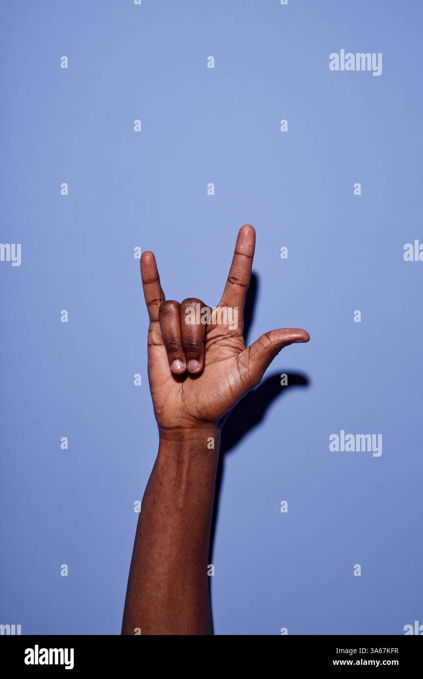 Close-up of African American hand making rock and roll gesture against ...