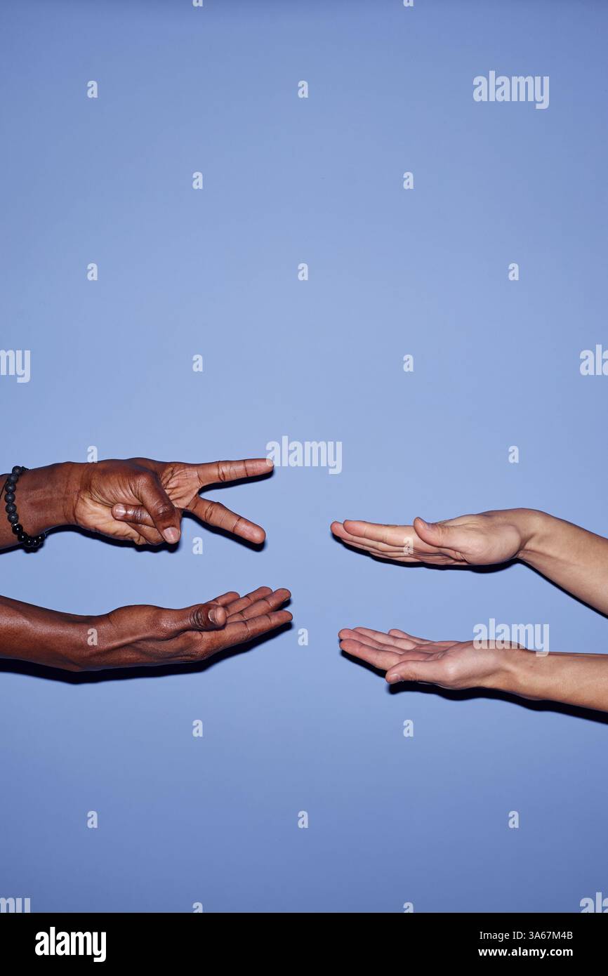 Two hands facing each other against blue background, one making peace ...