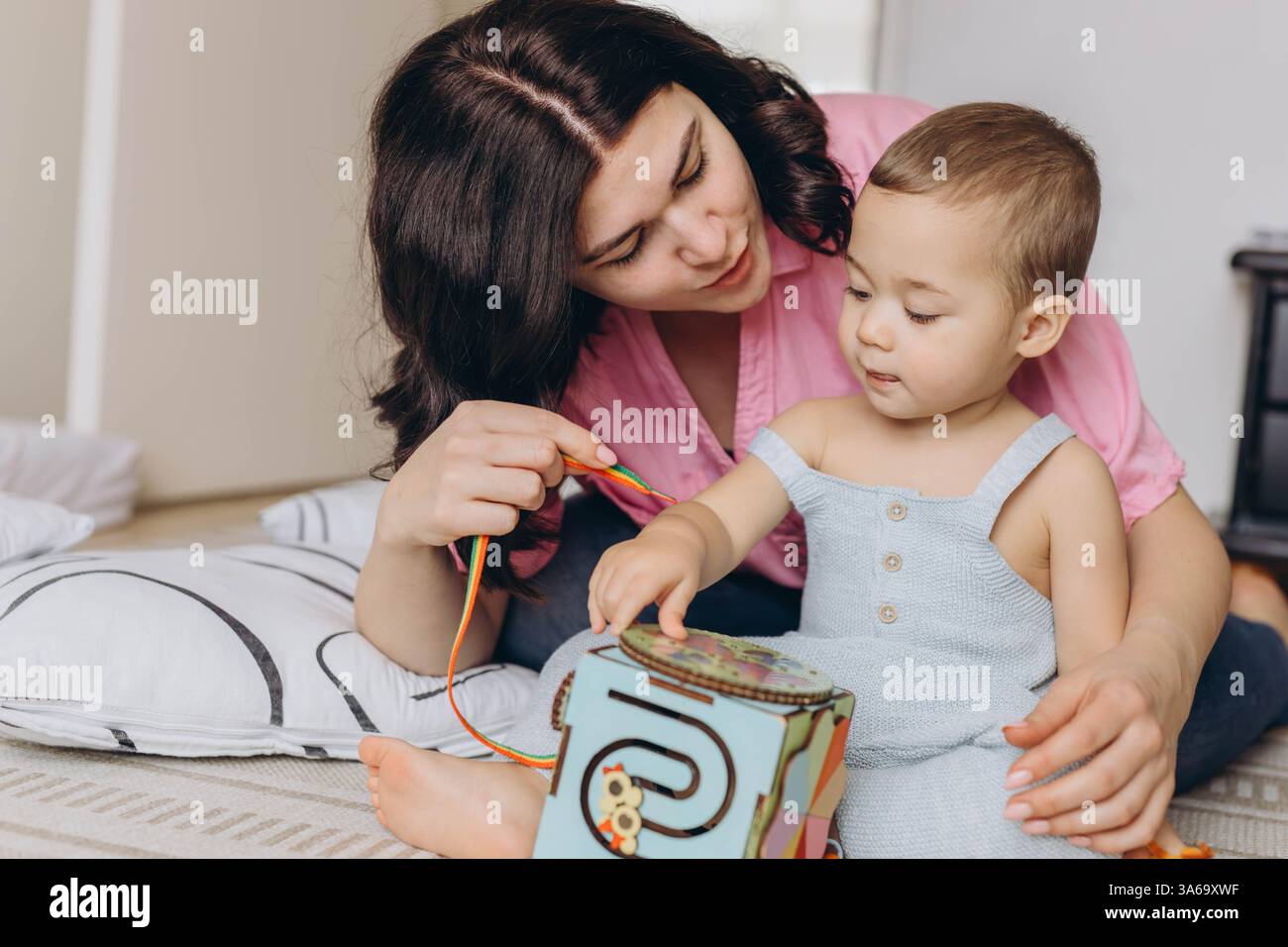 Mother and baby playing together with developmental toys,sitting in ...