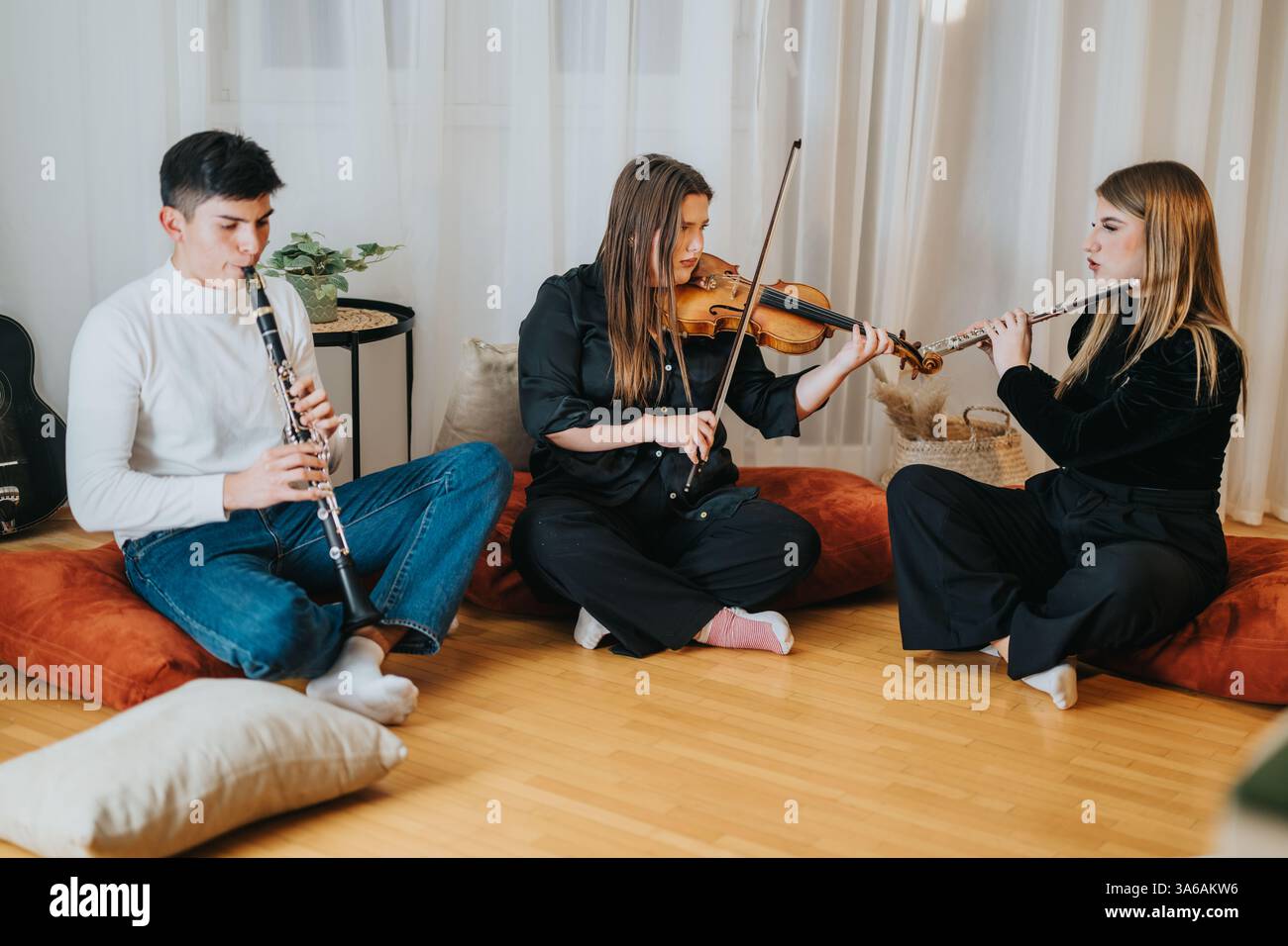 Group of young adults playing musical instruments together in a cozy ...