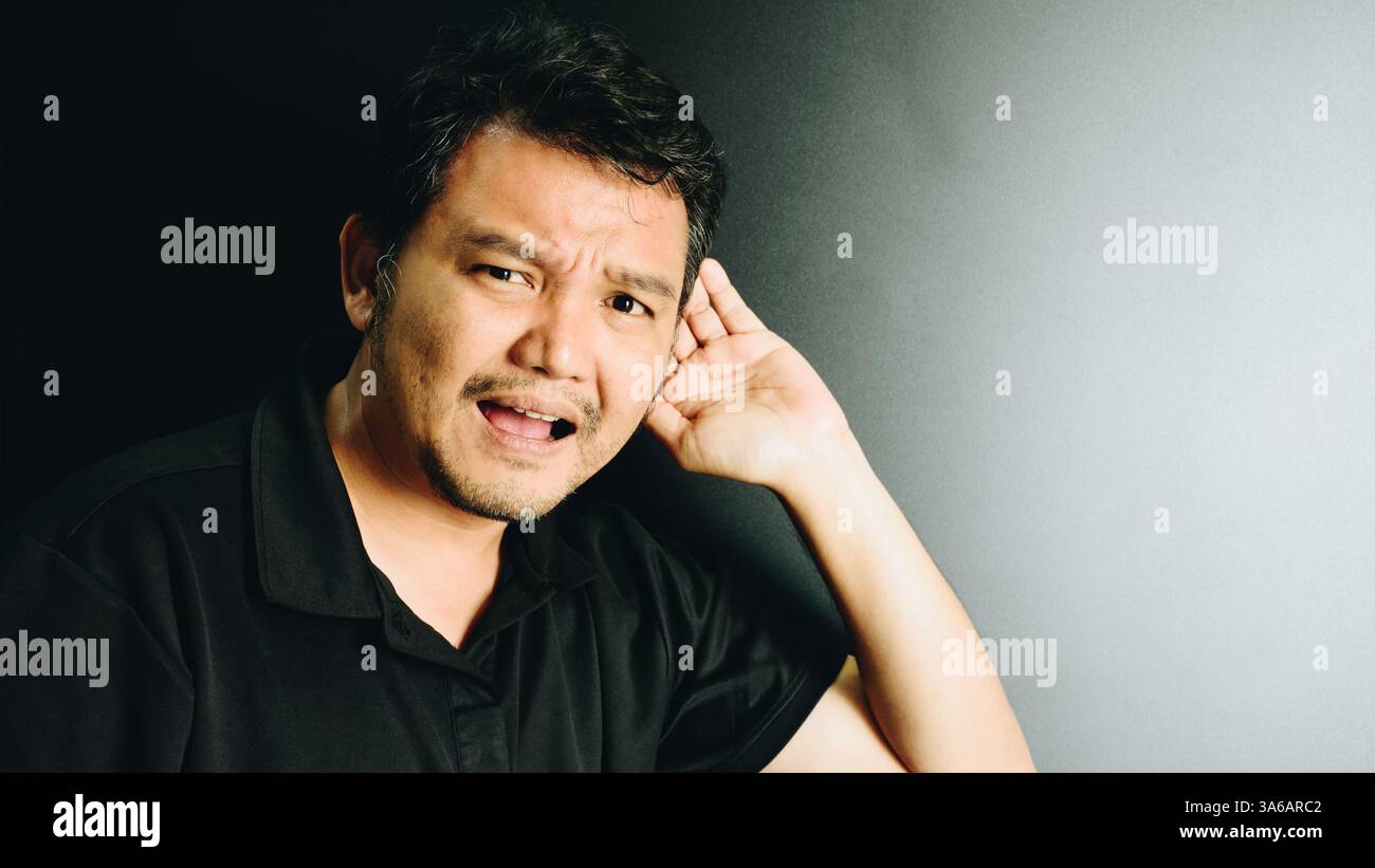 Asia man 40s in black polo shirt have a deaf or hearing with listening ...