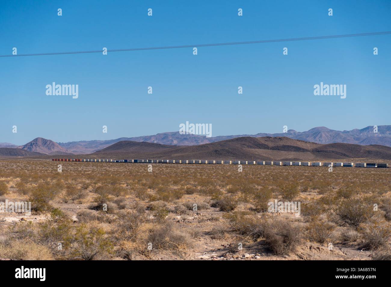 A train travels through the desert with mountains behind in California ...