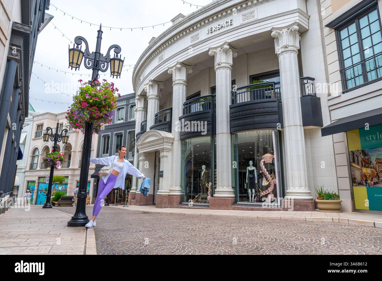 A woman is posing with purple leggings and white shirt in front of an ...