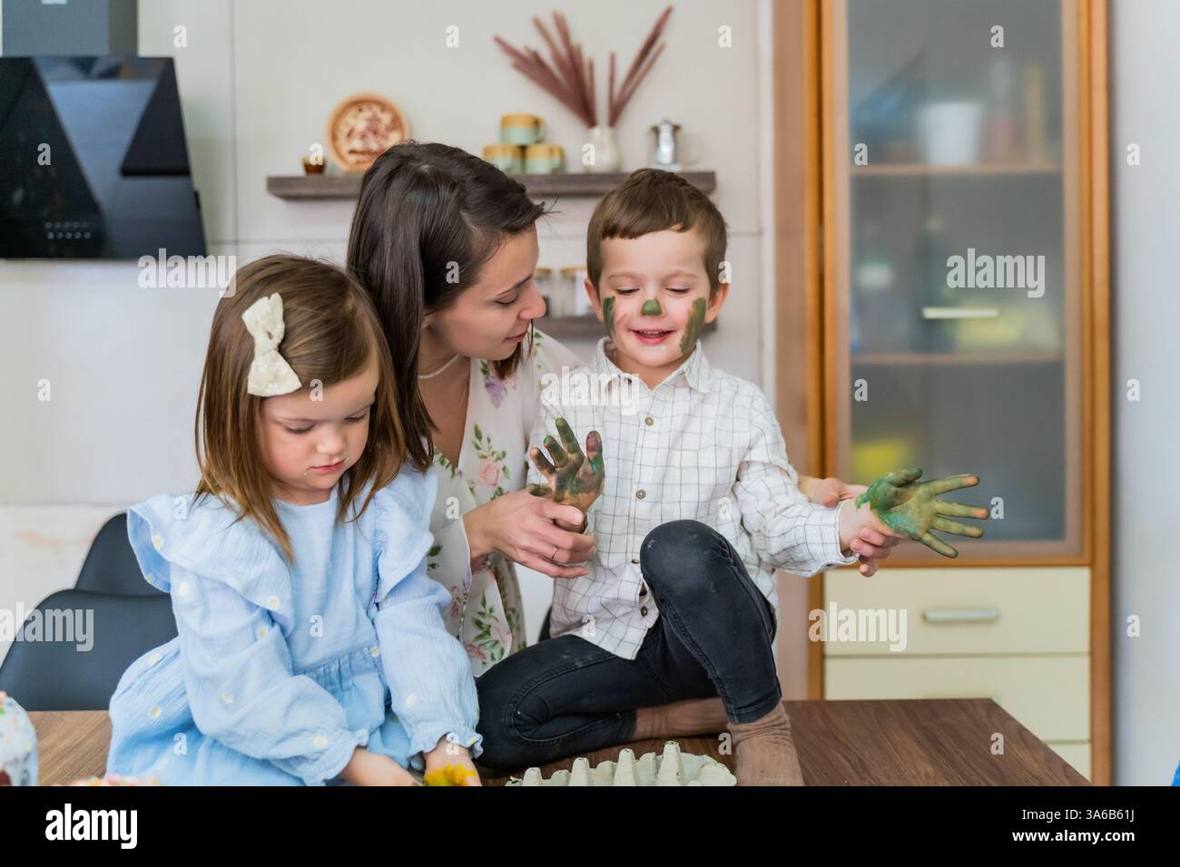 Mom and children in the kitchen have fun before Easter. Easter Eve ...