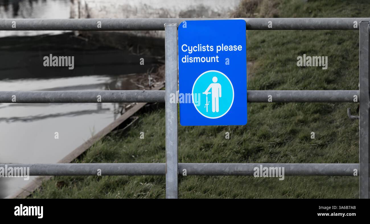 Cyclists Dismount sign on gate by water Stock Photo - Alamy