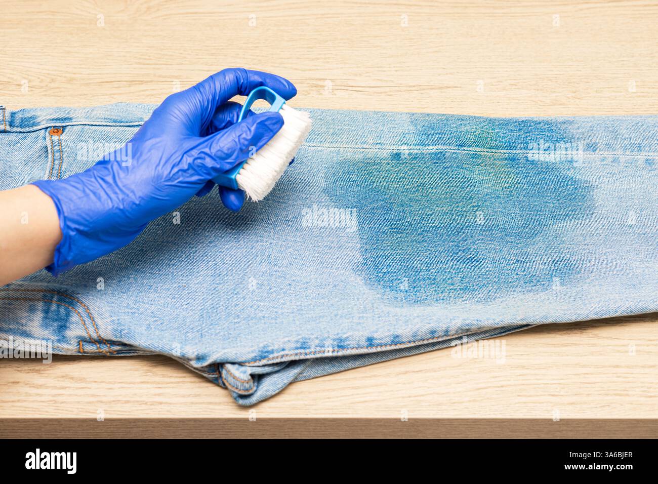 man cleaning jeans from dirt with a brush. woman removing dirty stain ...