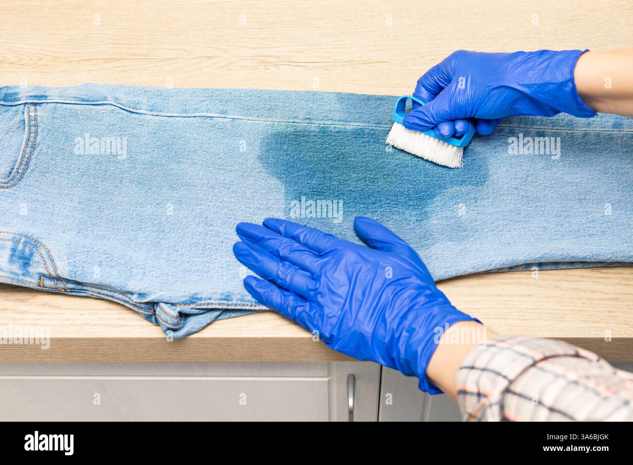 man cleaning jeans from dirt with a brush. woman removing dirty stain ...